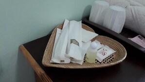 Uma bandeja com artigos de higiene pessoal sobre uma mesa em um quarto com parede verde-clara.