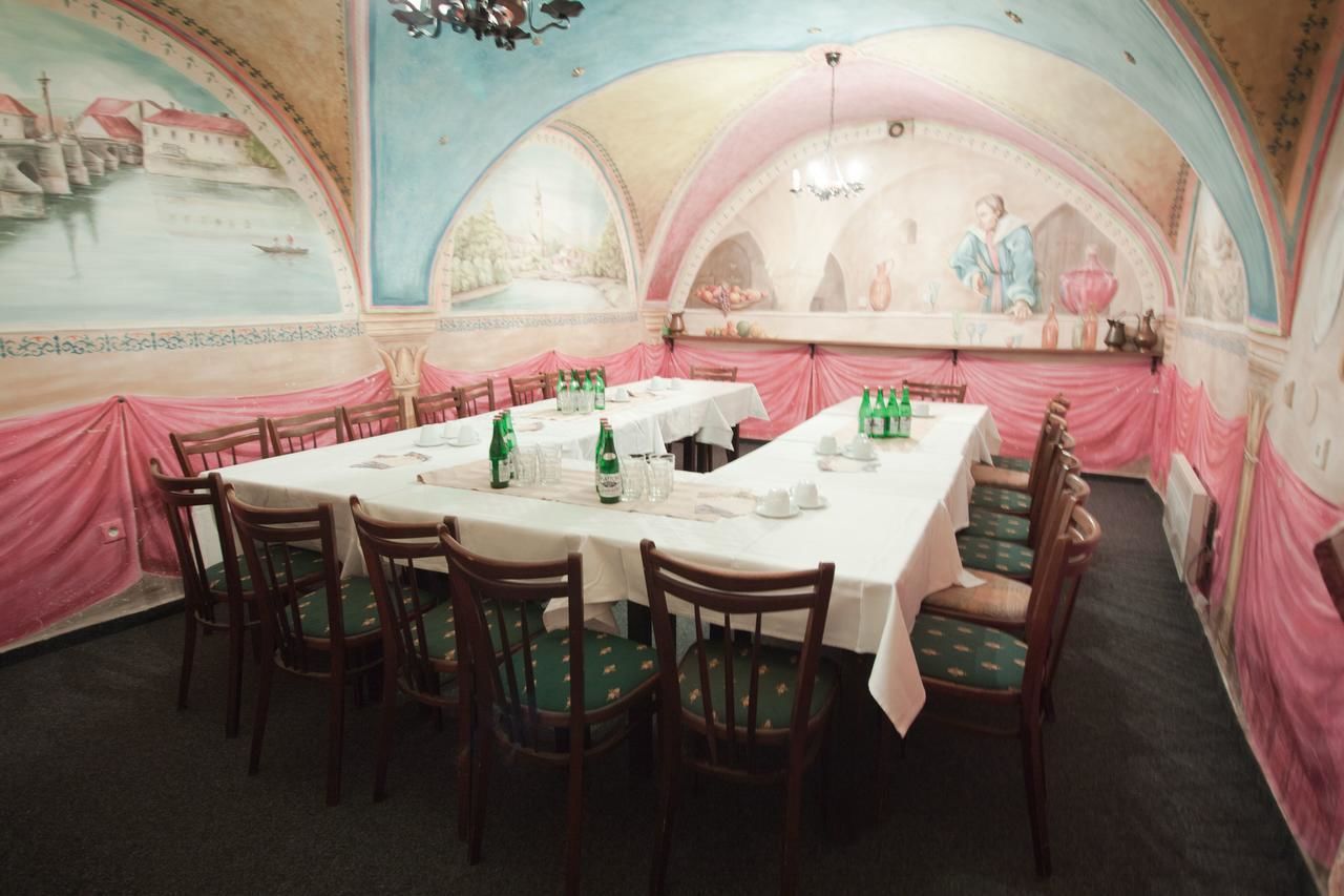 Uma sala de jantar com uma mesa comprida posta para refeição, rodeada por cadeiras com estofamento verde.