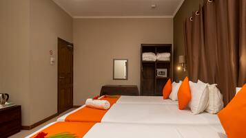 Quarto de hotel com uma cama grande, um guarda-roupa de madeira, um espelho e uma mesa de cabeceira com abajur.