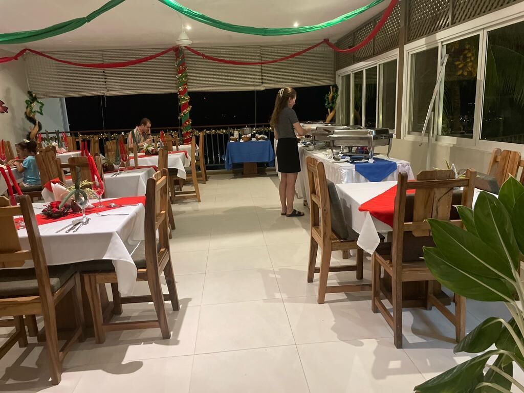 Um restaurante com várias mesas e cadeiras, algumas com toalhas de mesa vermelhas.
