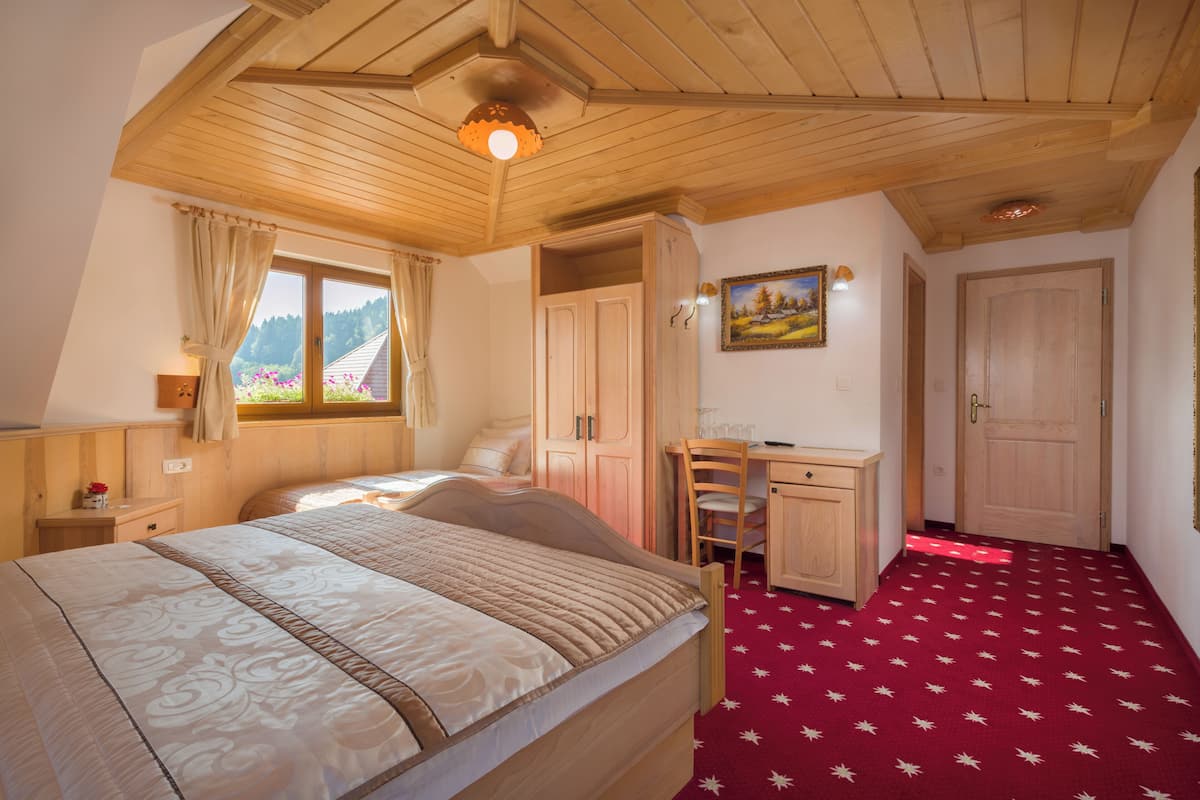 Um quarto com teto de madeira, uma cama, uma escrivaninha e uma cadeira.