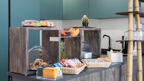 Buffet de café da manhã com diversos alimentos e uma pequena planta em vaso.