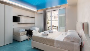 Quarto moderno com uma cama grande, um sofá, uma TV de tela plana e uma porta de vidro deslizante para uma área externa.