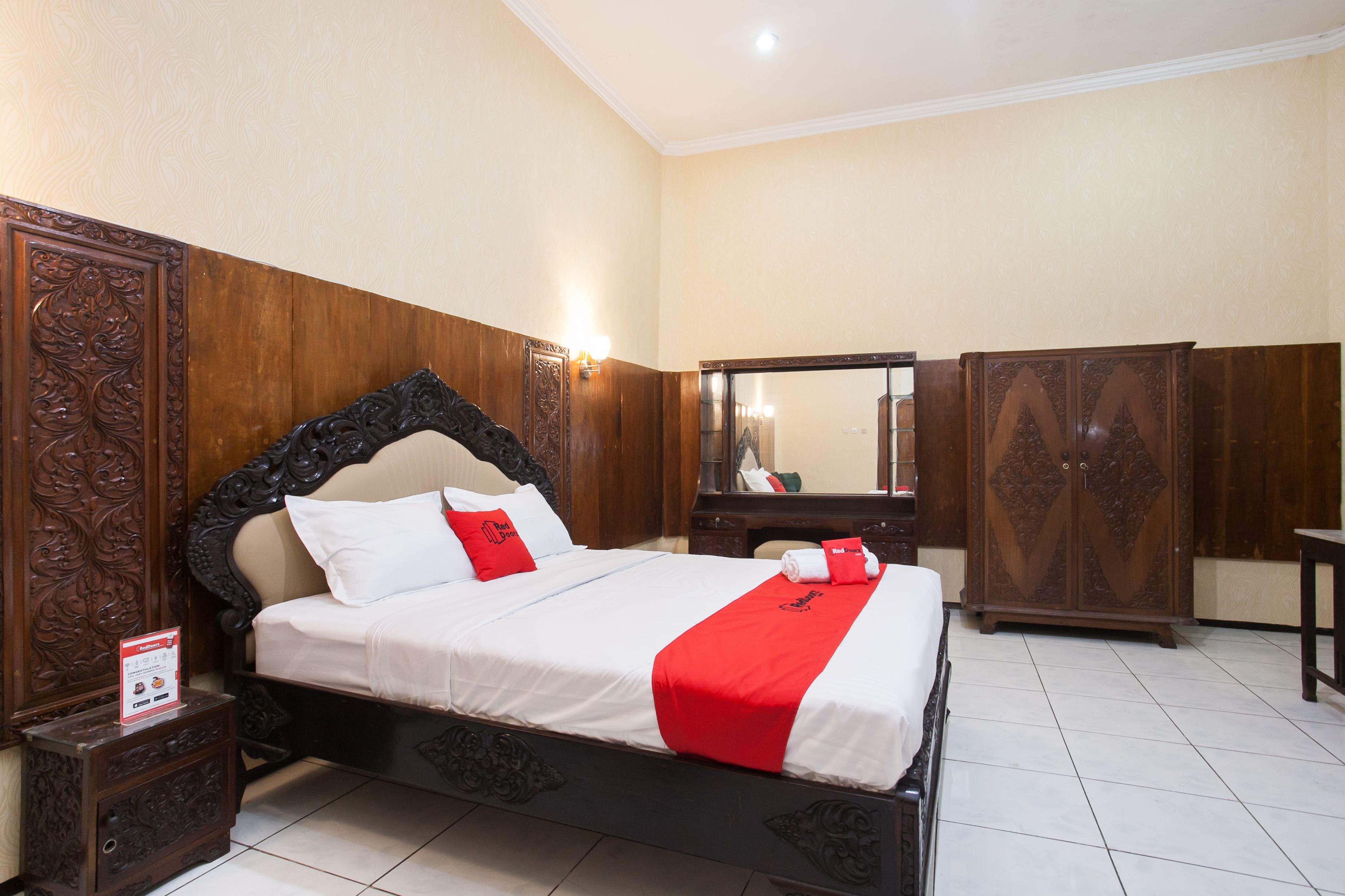 Quarto de hotel com uma cama grande, cabeceira de madeira e um guarda-roupa.