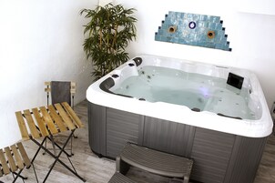 Uma área de spa com hidromassagem, assentos de madeira e uma planta em vaso.