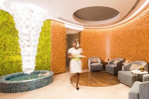 Um interior moderno com uma área de estar circular, uma parede com jardim vertical verde e um design de teto único.