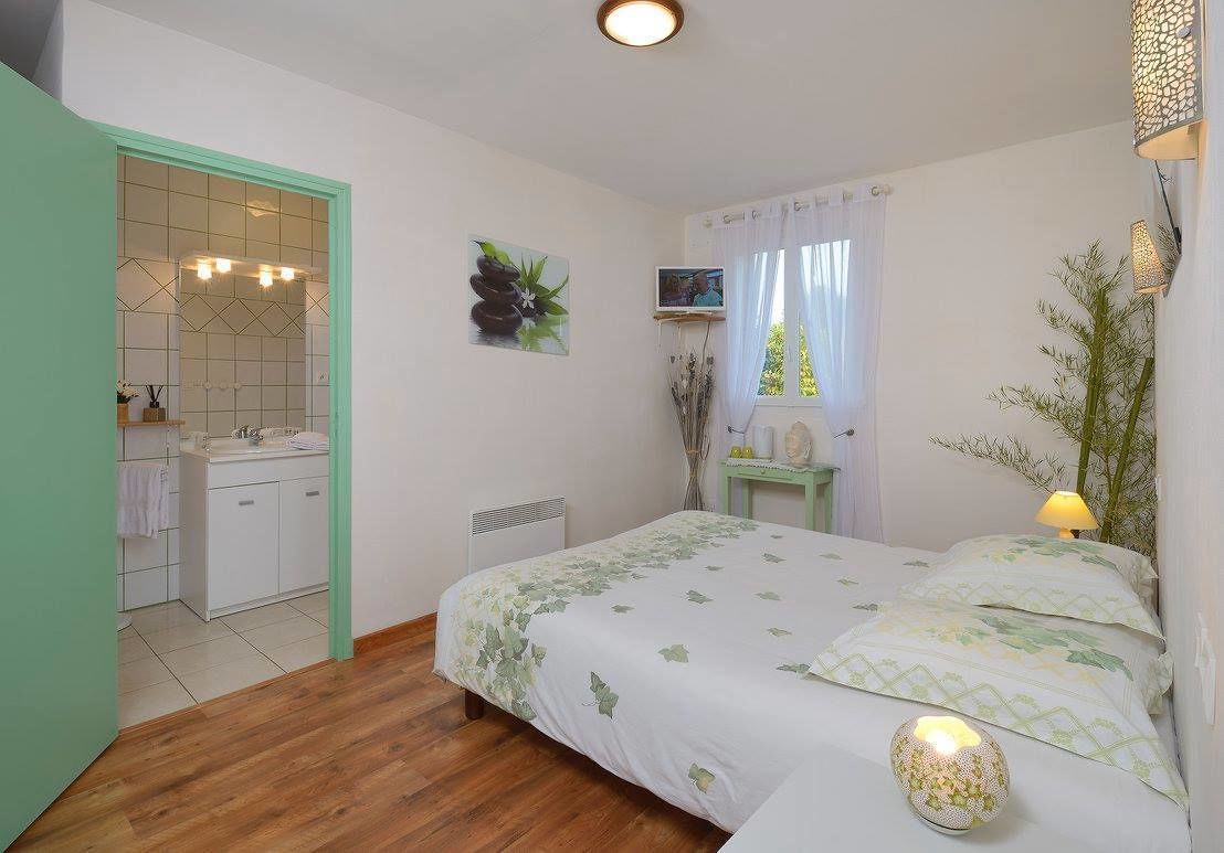 Quarto com cama, luminária de cabeceira e janela com cortinas.