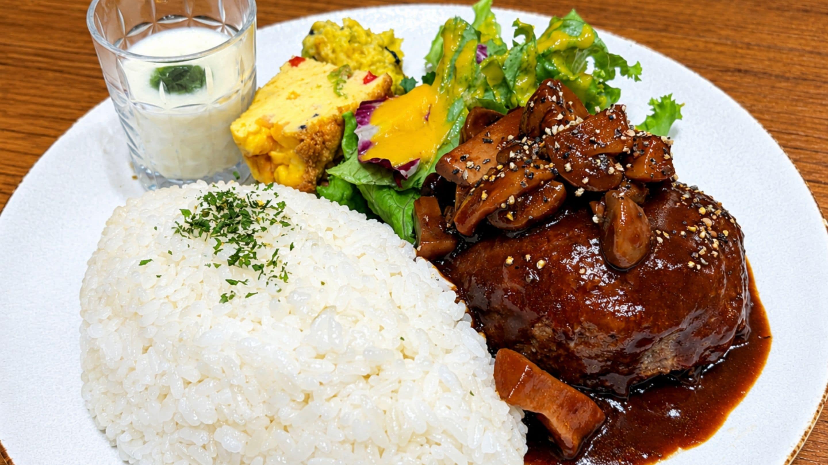Um prato com arroz branco, um ensopado de carne e uma salada.
