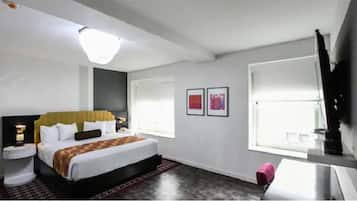 Quarto de hotel moderno com uma cama grande, mesas de cabeceira, escrivaninha e televisão.