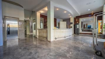 Um hall amplo com piso de mármore, balcão de recepção e geladeira.