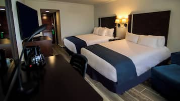 Quarto de hotel com duas camas, uma escrivaninha, uma máquina de café e uma televisão.