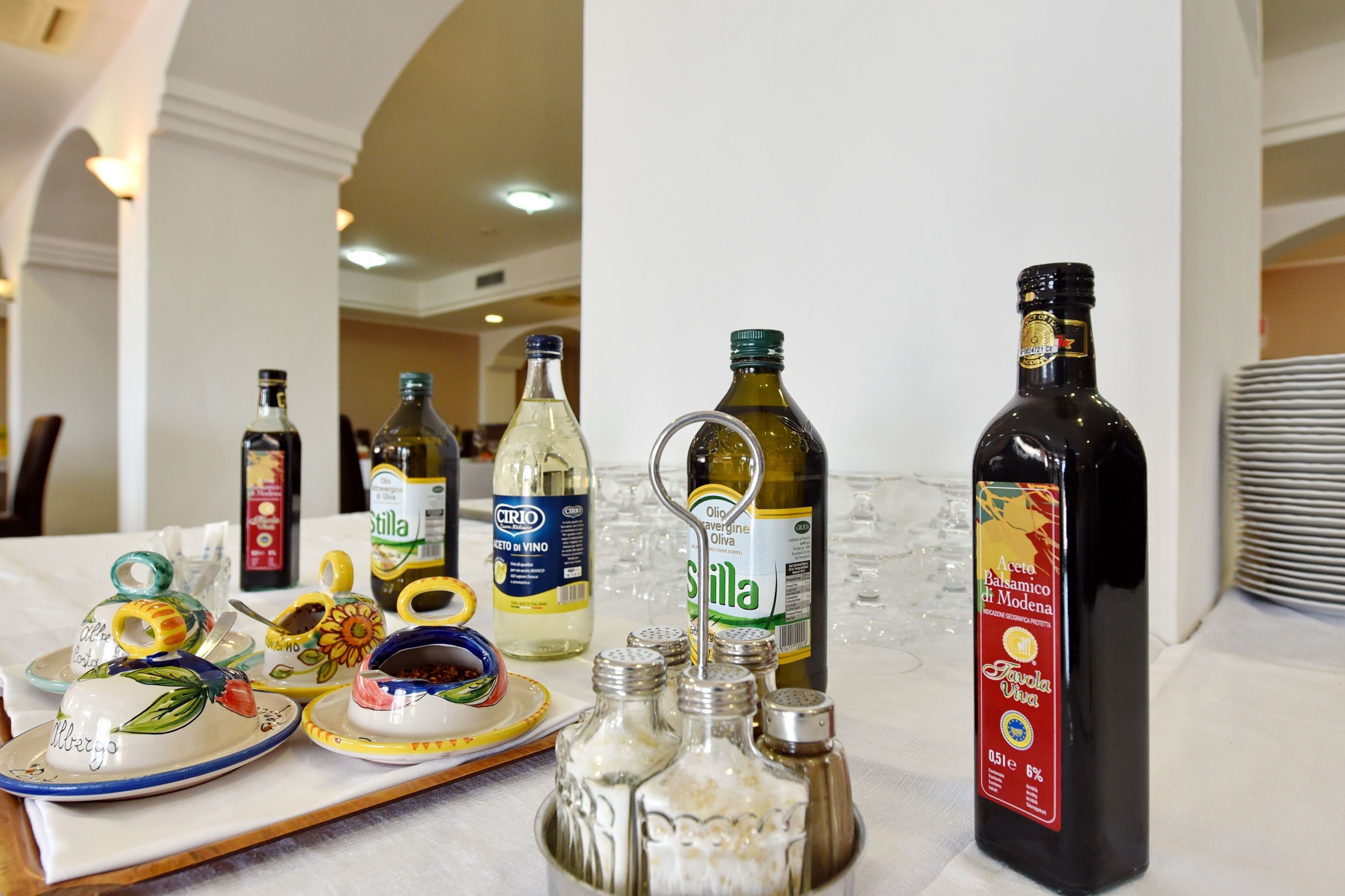 Uma mesa com várias garrafas de azeite e saleiros, juntamente com pratos de cerâmica.
