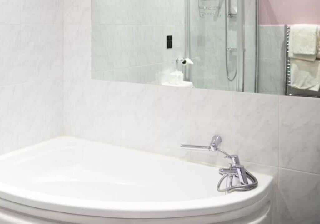 Um banheiro moderno com banheira branca, box de vidro e um espelho grande.