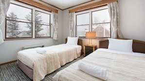 Quarto de hotel com duas camas, uma janela com cortinas, um abajur e um radiador.