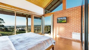 Quarto com uma cama grande, parede de tijolos e vista para a paisagem.