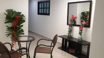 Quarto moderno com mesa redonda, duas cadeiras, um aparador com espelho e plantas em vasos.