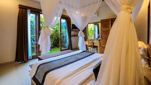Quarto com cama, escrivaninha e cadeira. Possui janela com cortinas e vista para o verde lá fora.