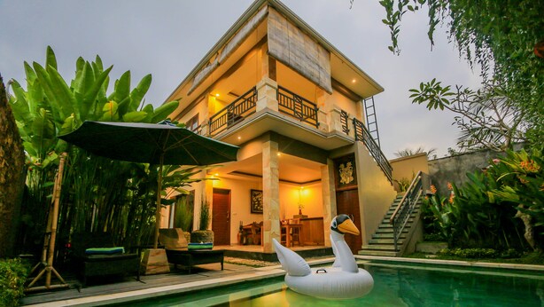 Uma casa de dois andares com piscina, um brinquedo de cisne e uma escadaria para o andar superior.