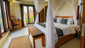 Quarto com cama, um banco e vista para um edifício através de uma janela.