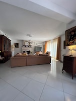 Uma sala de estar com sofá, televisão, lareira e lustre.