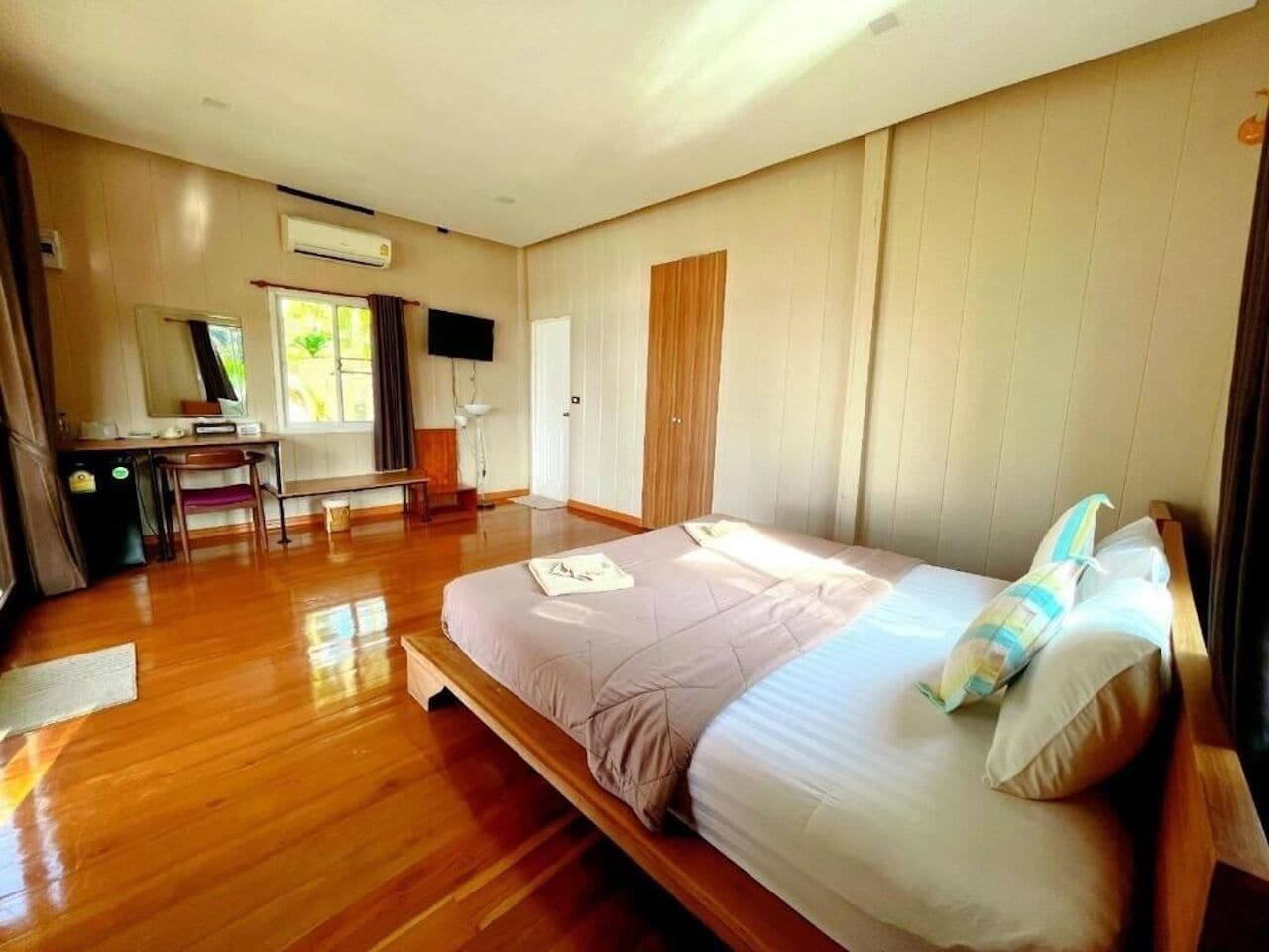 Quarto com cama, escrivaninha, cadeira e televisão.