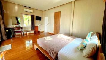 Quarto com cama, escrivaninha, cadeira e televisão.
