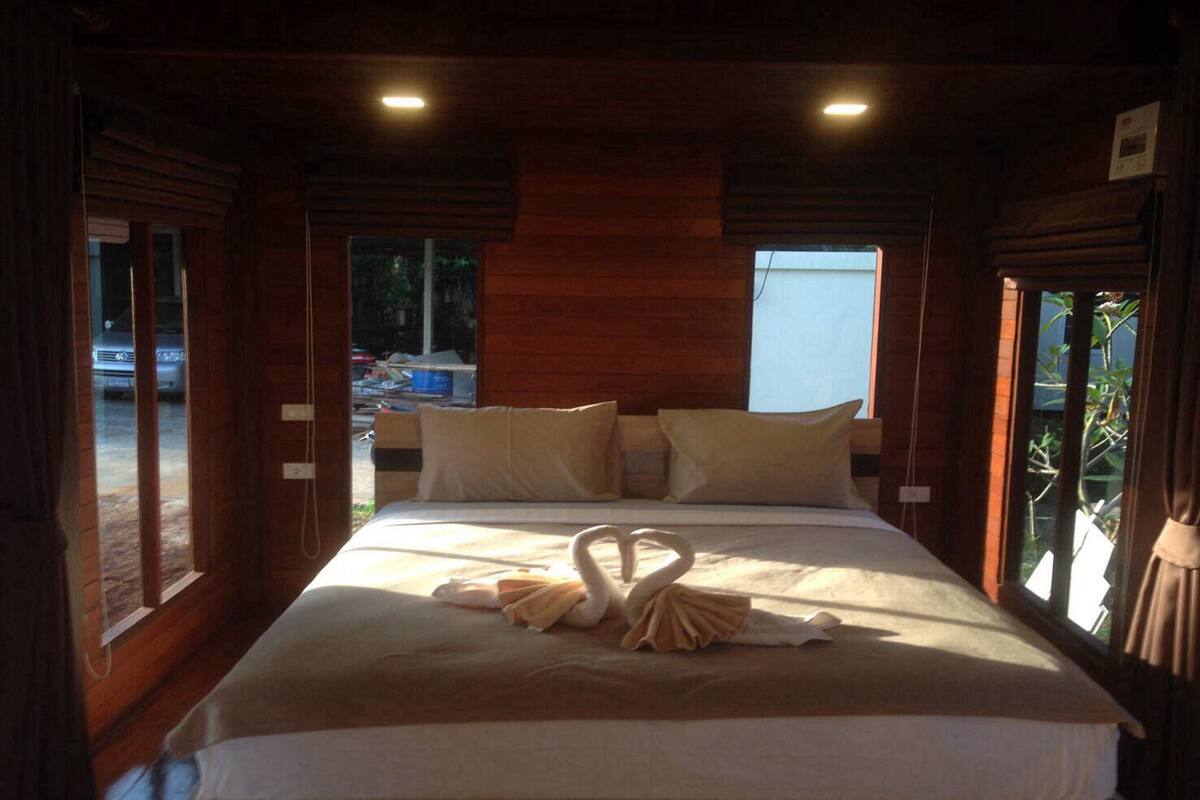 Quarto de hotel com uma cama grande, paredes de madeira e vista para o exterior.