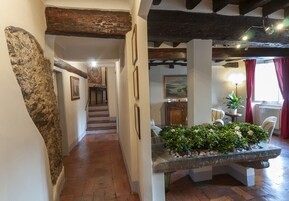 Um banco de pedra com plantas, uma escadaria e uma área de refeições com cadeiras e uma mesa.