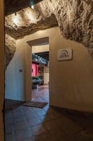 Corredor de paredes de pedra que leva a um quarto com uma placa indicando 'B&B ARENA'.