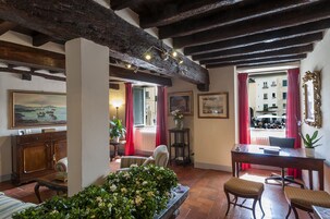 Um quarto aconchegante com teto de madeira, uma mesa de jantar, cadeiras, um sofá, uma planta em vaso e obras de arte nas paredes.