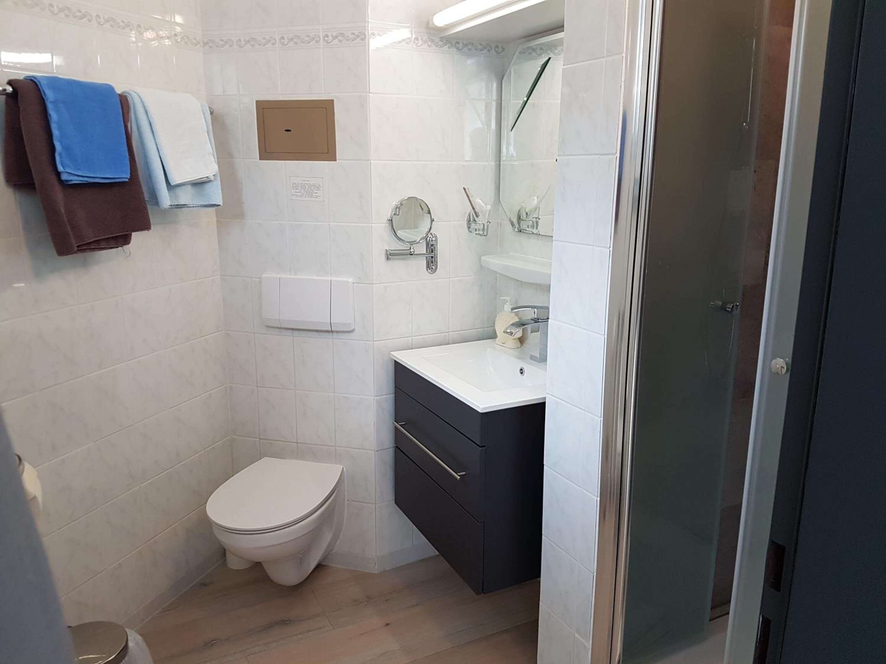 Uma casa de banho moderna com sanita, lavatório e chuveiro.