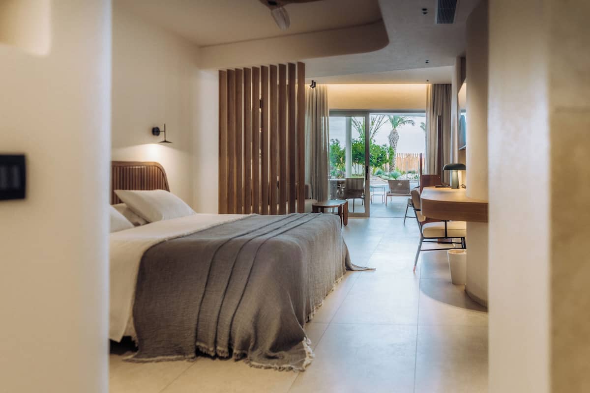 Quarto de hotel moderno com cama grande, área de refeições e vista para o exterior.