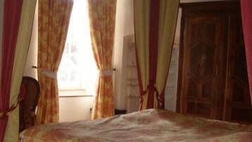 Quarto com cama, cortinas e porta de madeira.