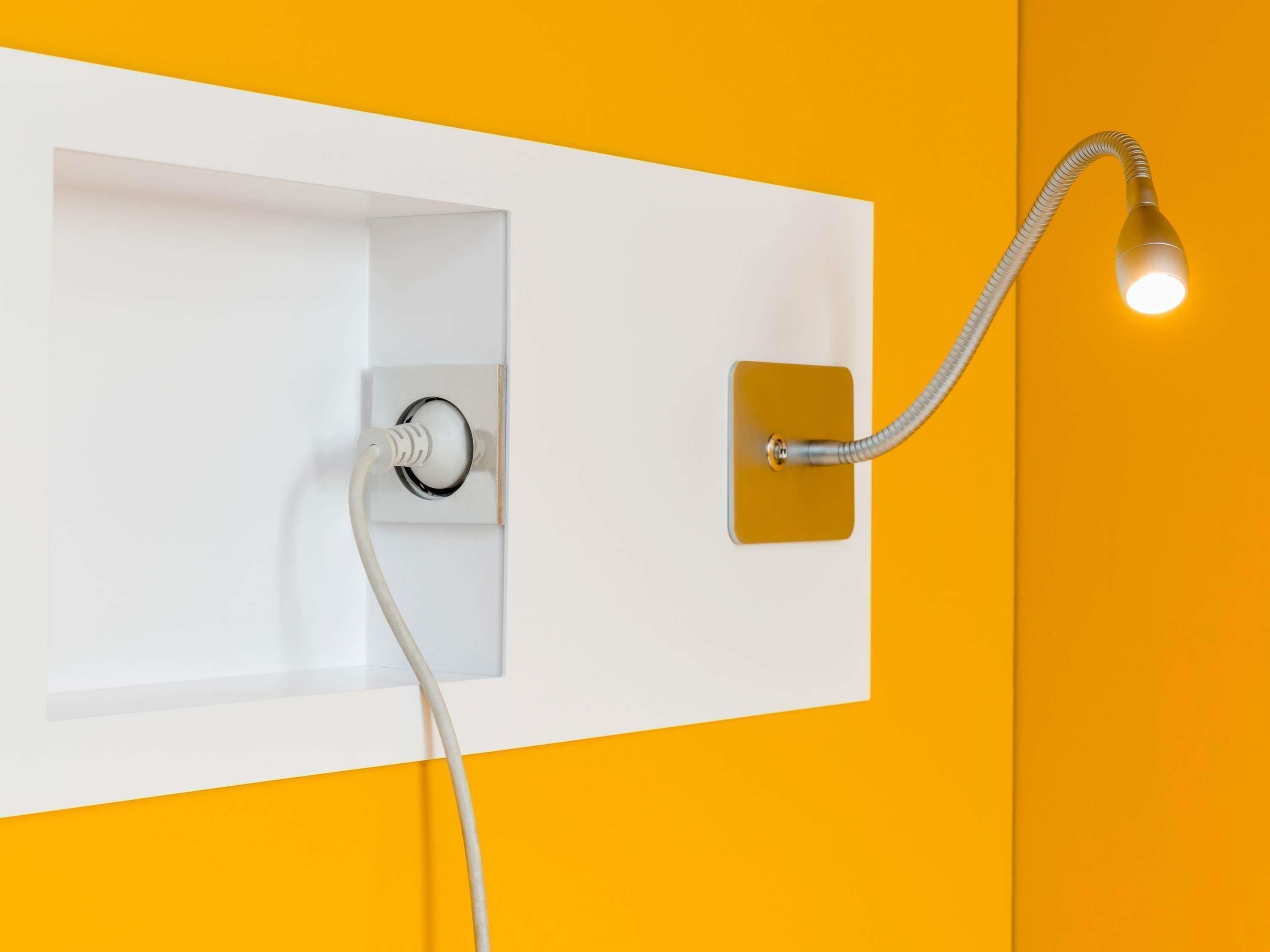 Chuveiro fixado na parede, com mangueira flexível e luminária.