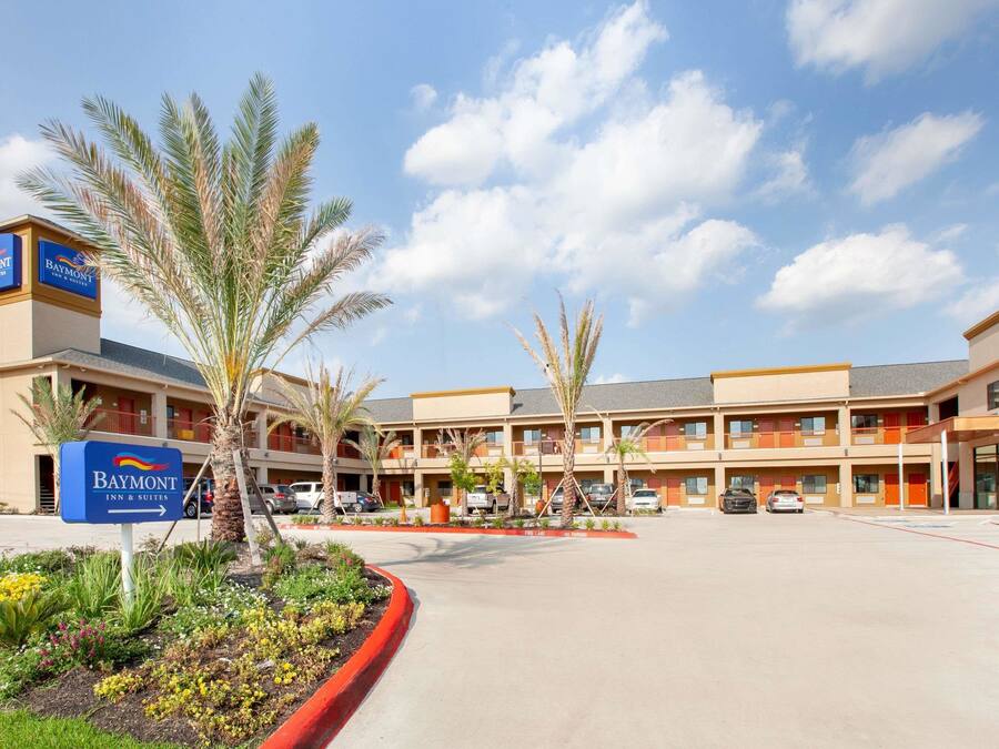 Um Baymont Inn & Suites com estacionamento, vários andares e céu claro.