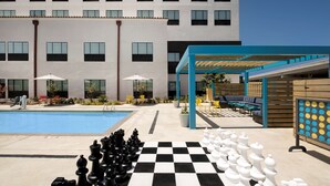 Um hotel com piscina, área de estar ao ar livre e um tabuleiro de xadrez montado para jogar.