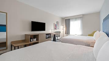 Quarto de hotel com duas camas, televisão, secretária com micro-ondas e uma cadeira.