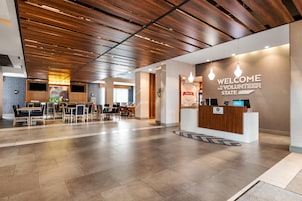 Um lobby moderno com teto de madeira, balcão de recepção e área de bar.