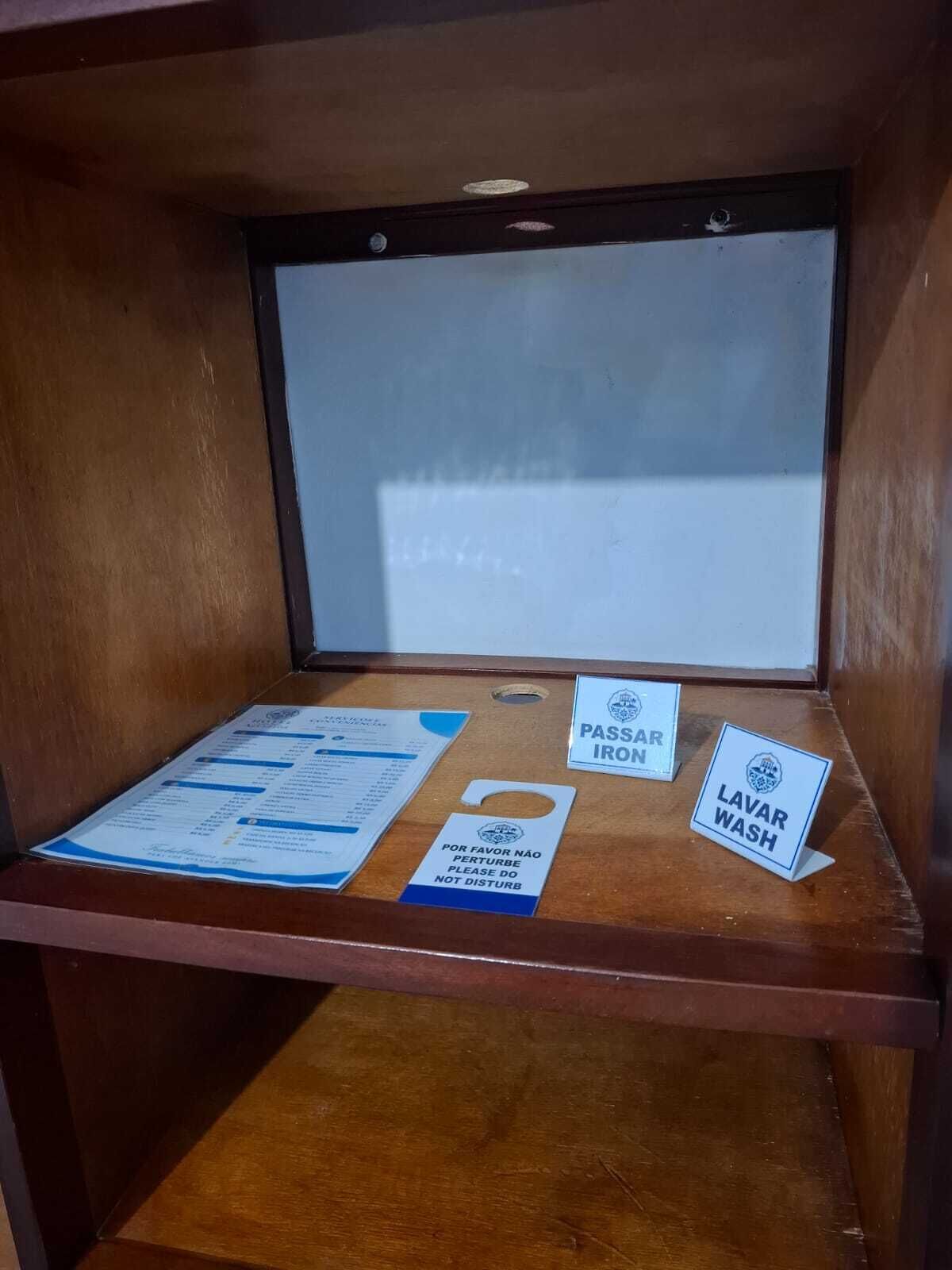 Um balcão de madeira com um menu, uma placa com 'Passar Iron' e uma placa com 'Lavar Wash'.