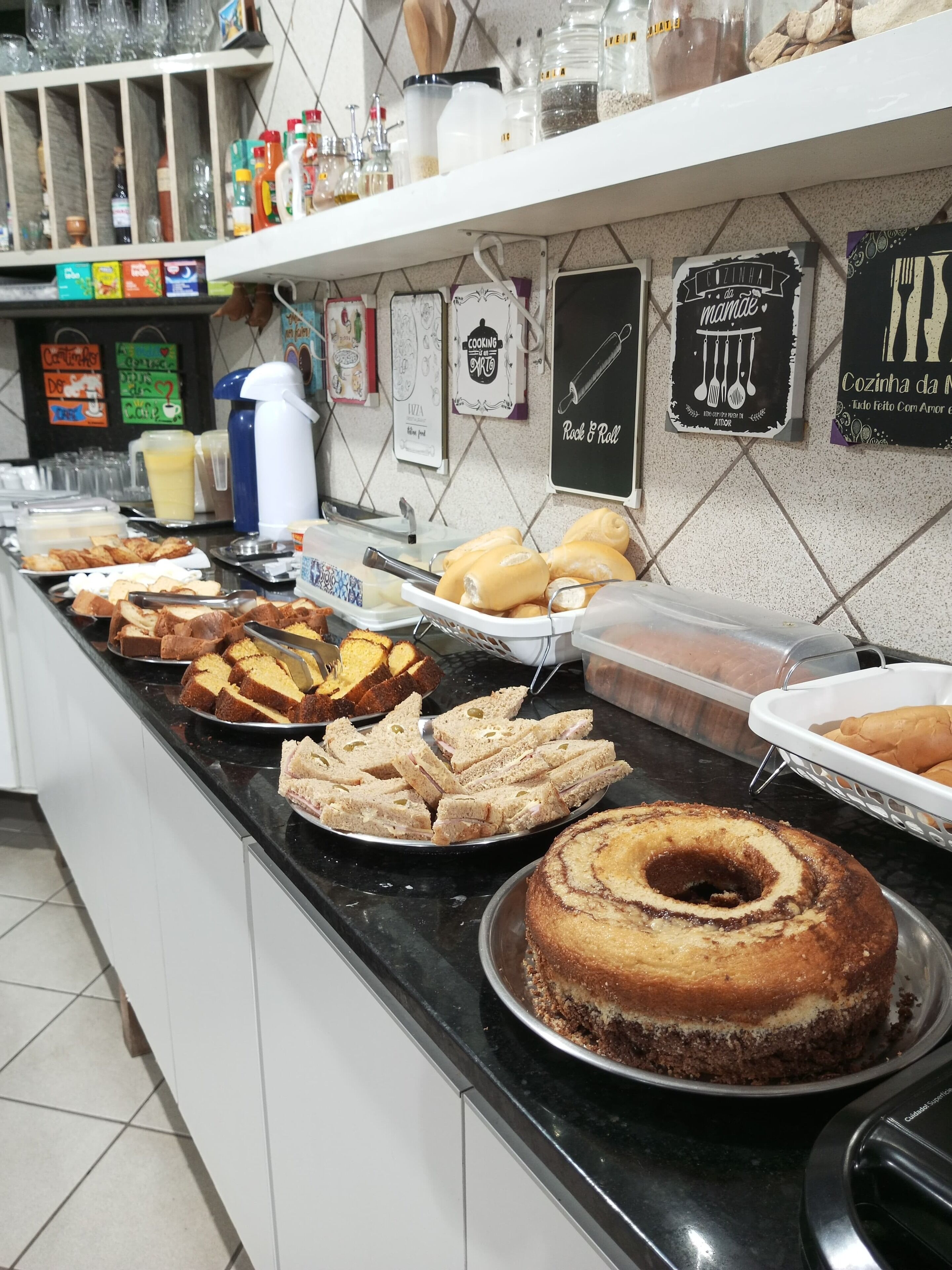 Balcão de buffet com diversas opções de comida, como sanduíches, bolos e doces.