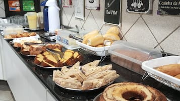 Balcão de buffet com diversas opções de comida, como sanduíches, bolos e doces.