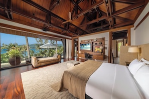 Um quarto espaçoso com uma cama grande, uma televisão e vista para o oceano.