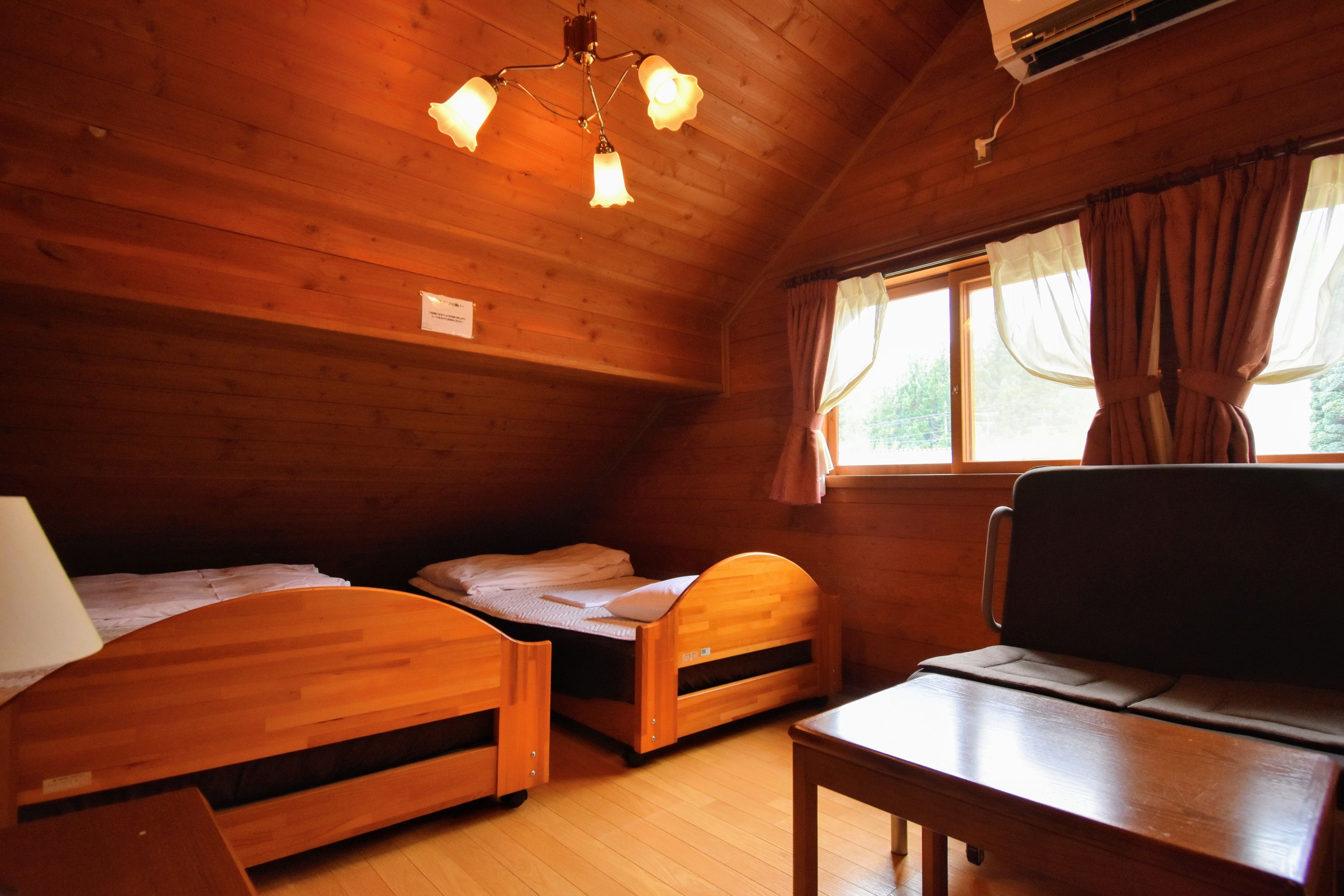 Uma cabana com duas beliches de madeira, uma mesa de madeira e um banco.