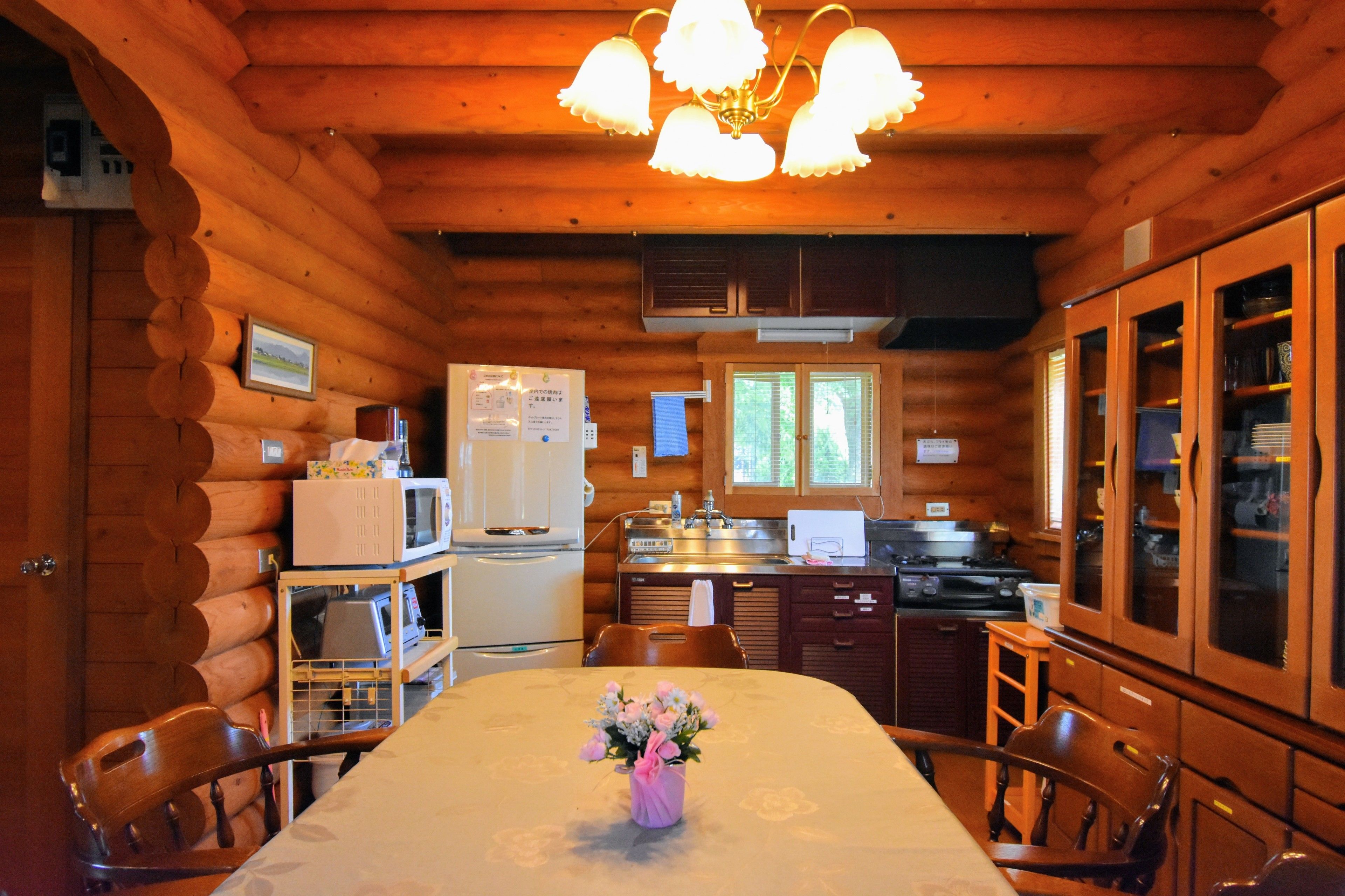 Interior de uma cabana de tronco com sala de jantar, cozinha e armários embutidos.