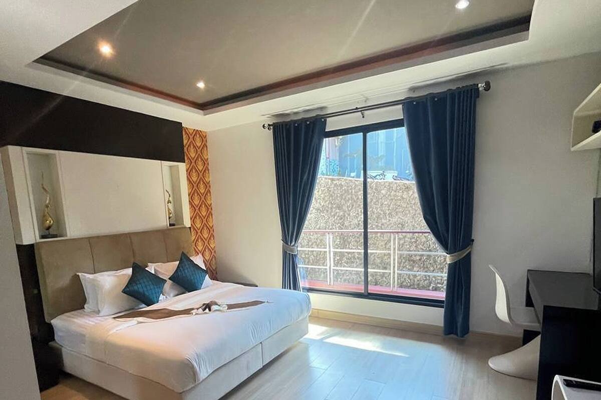 Quarto de hotel moderno com uma cama grande, varanda e televisão.