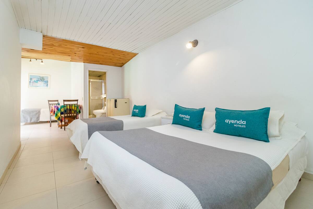 Quarto de hotel com duas camas, teto de madeira e vista para o exterior.