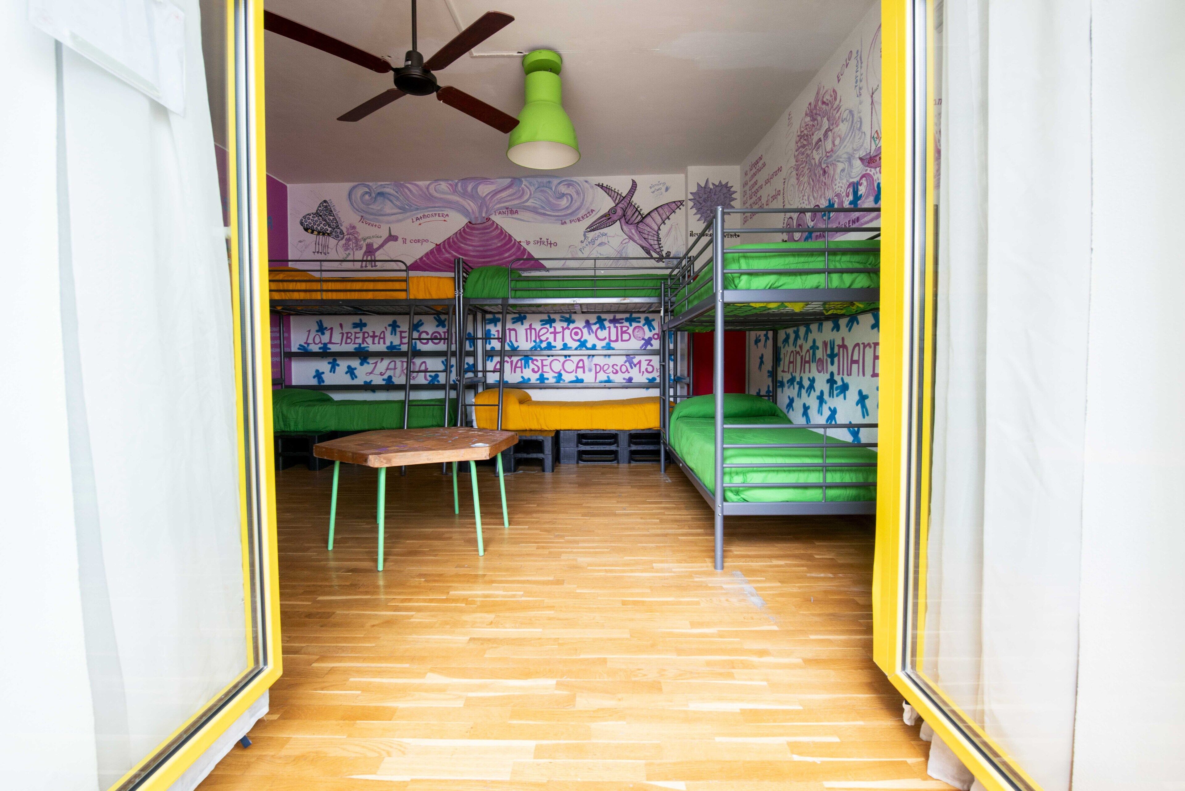 Quarto com beliches, ventilador de teto e piso de madeira.