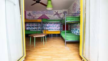 Quarto com beliches, ventilador de teto e piso de madeira.