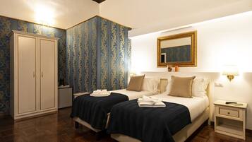 Quarto de hotel com duas camas, um guarda-roupa e um espelho.