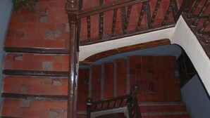 Uma escada de madeira com uma parede de tijolos de um lado e uma parede branca do outro.